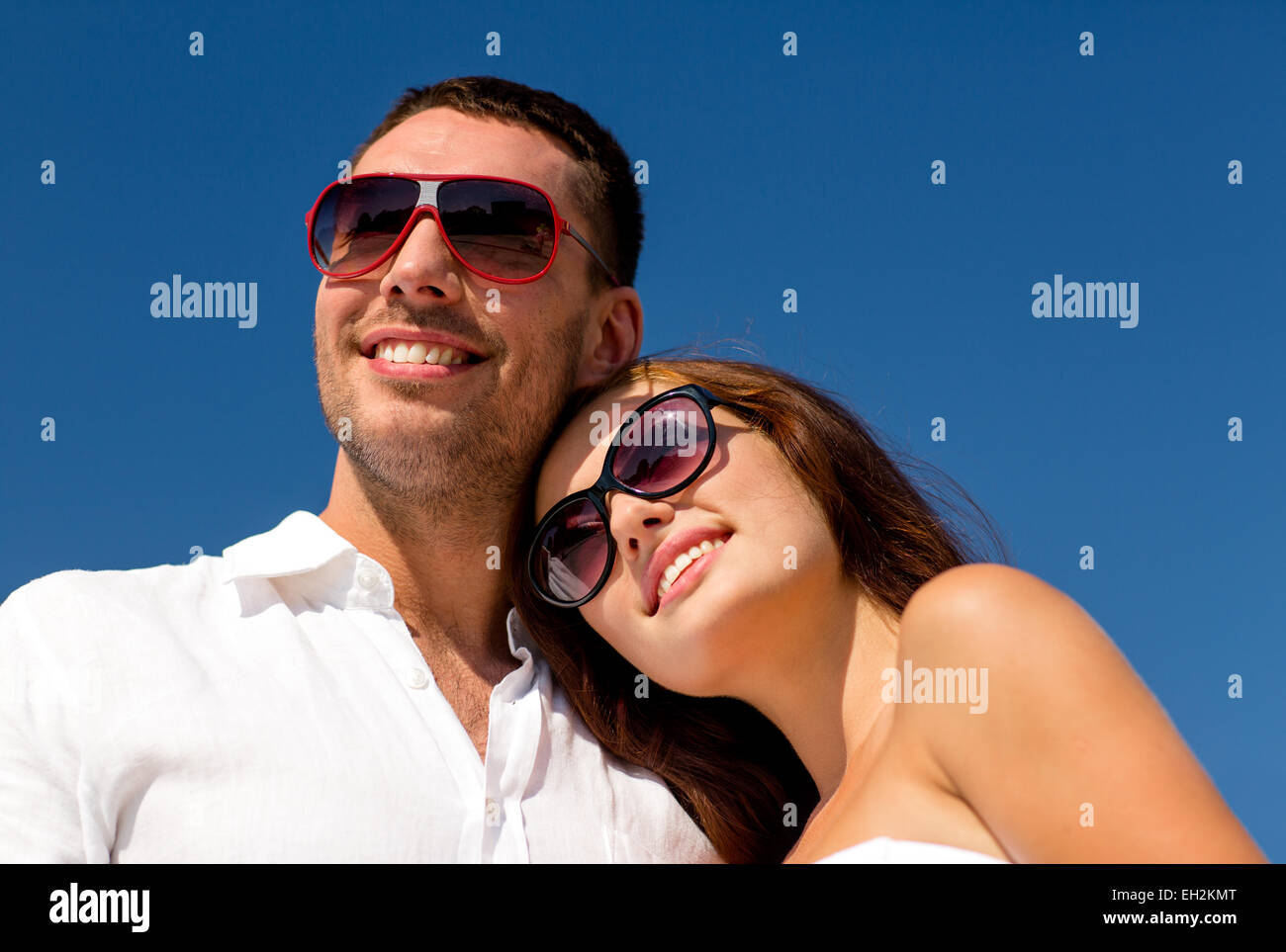 smiling couple over blue sky background Stock Photo - Alamy