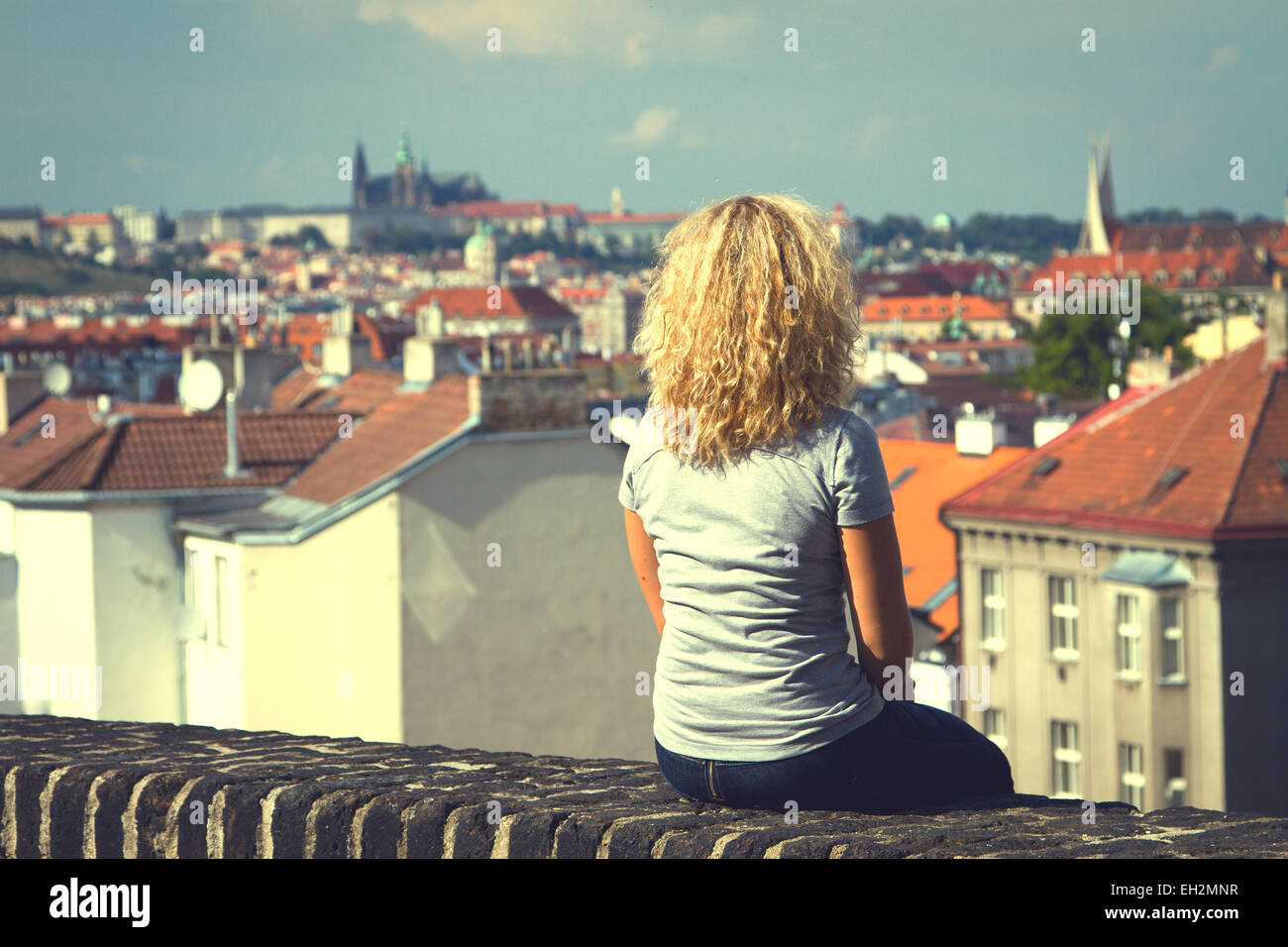 girl sitting on the roof of a house in Prague. top view of the city ...