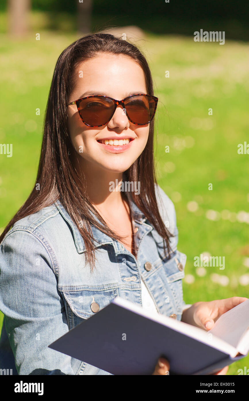 smiling young girl with book sitting in park Stock Photo - Alamy
