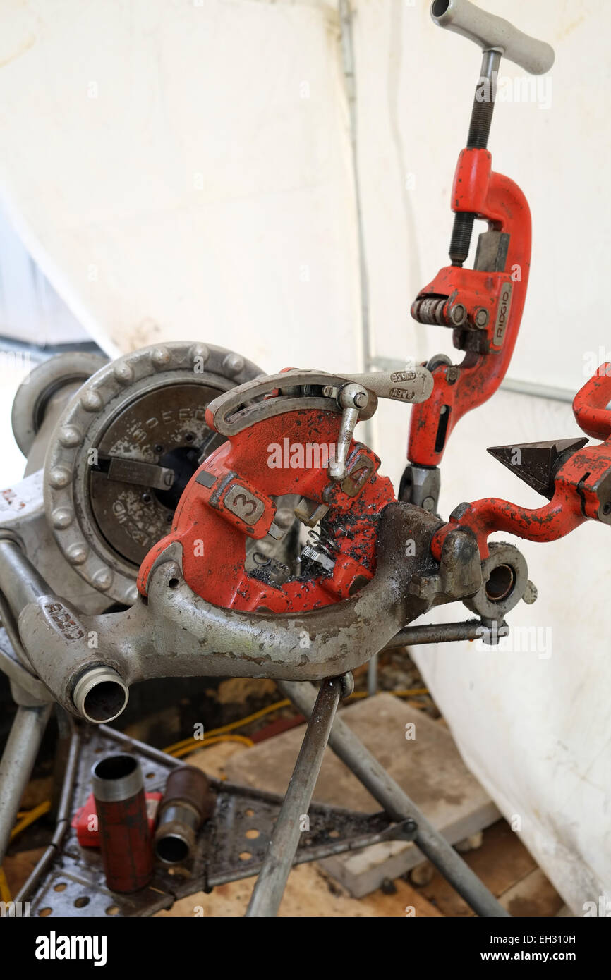 Metal pipe screw threading machine on a busy construction site. March ...