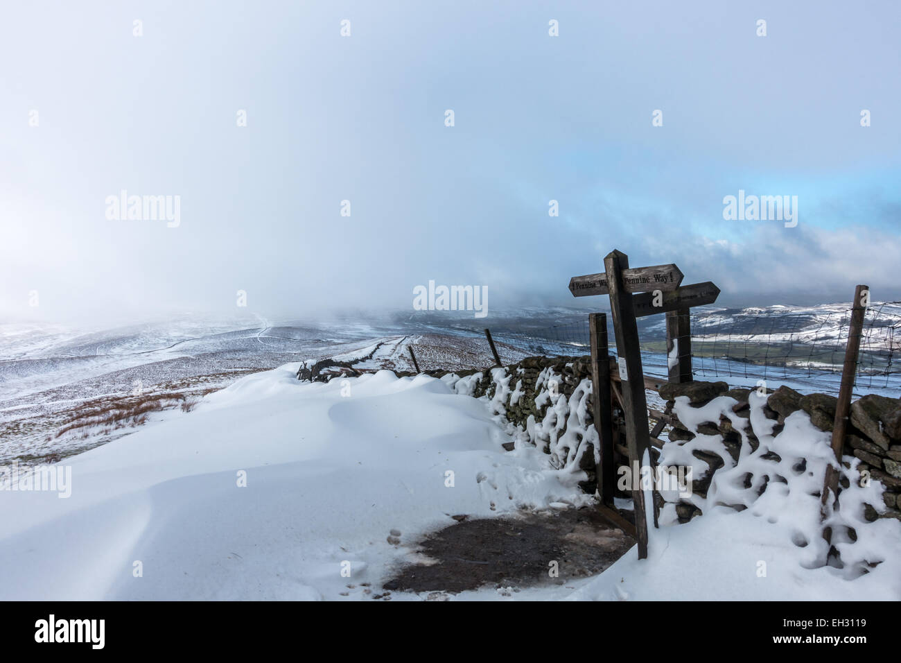 Path crossing wall on the snowy slopes of Pen-y-ghent in winter in the ...