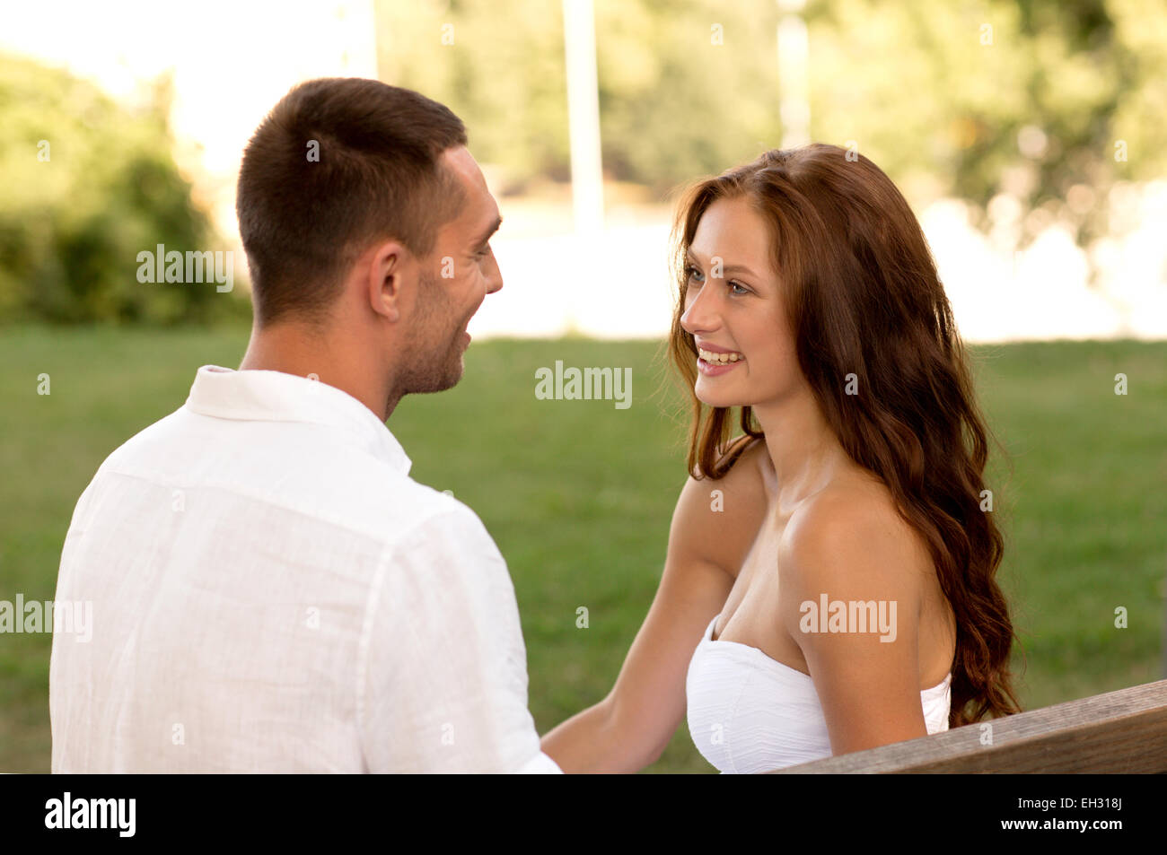 smiling couple sitting on bench in park Stock Photo - Alamy