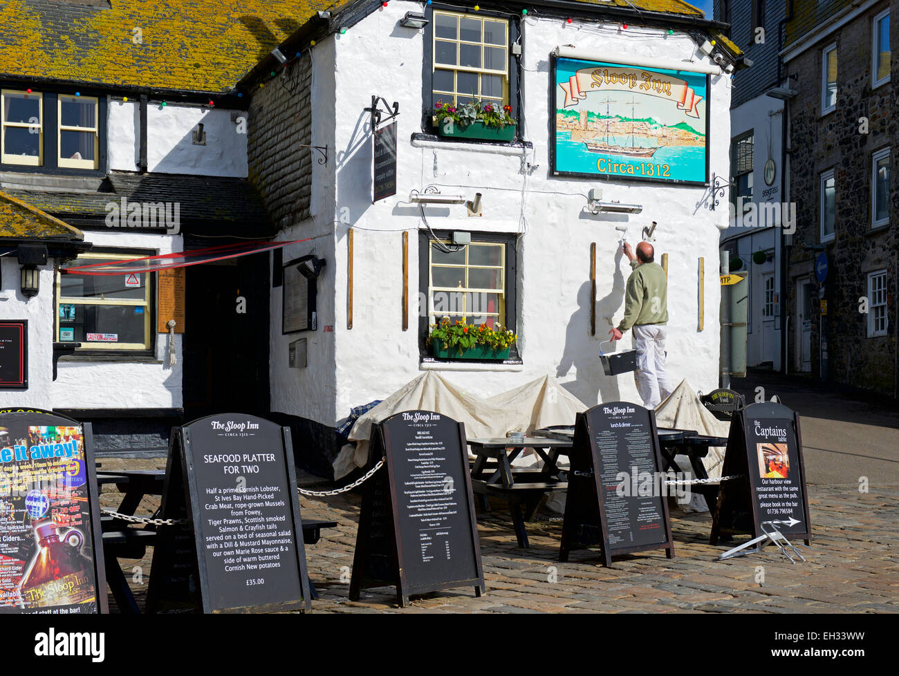 Man painting the walls of the Sloop Inn, St Ives, Cornwall, England UK ...