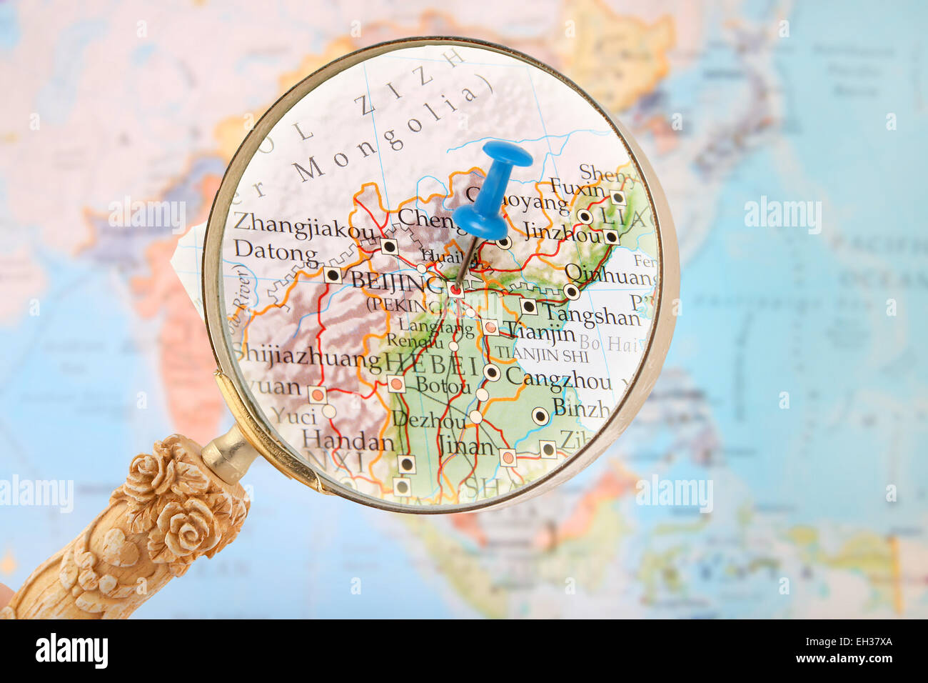 Blue tack on map of Asia with magnifying glass looking in on Beijing ...