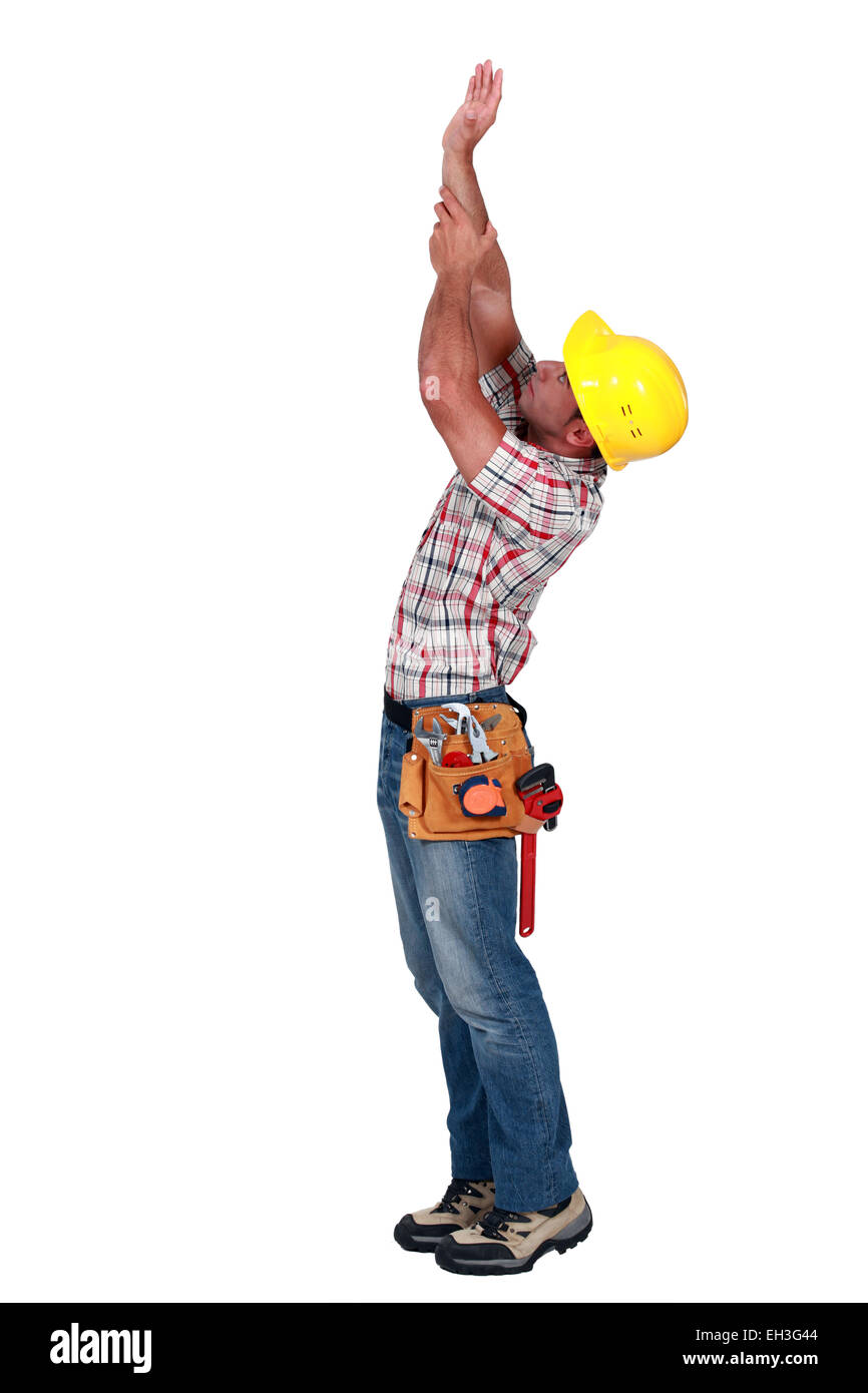 Laborer trying to touch the ceiling, studio shot Stock Photo - Alamy