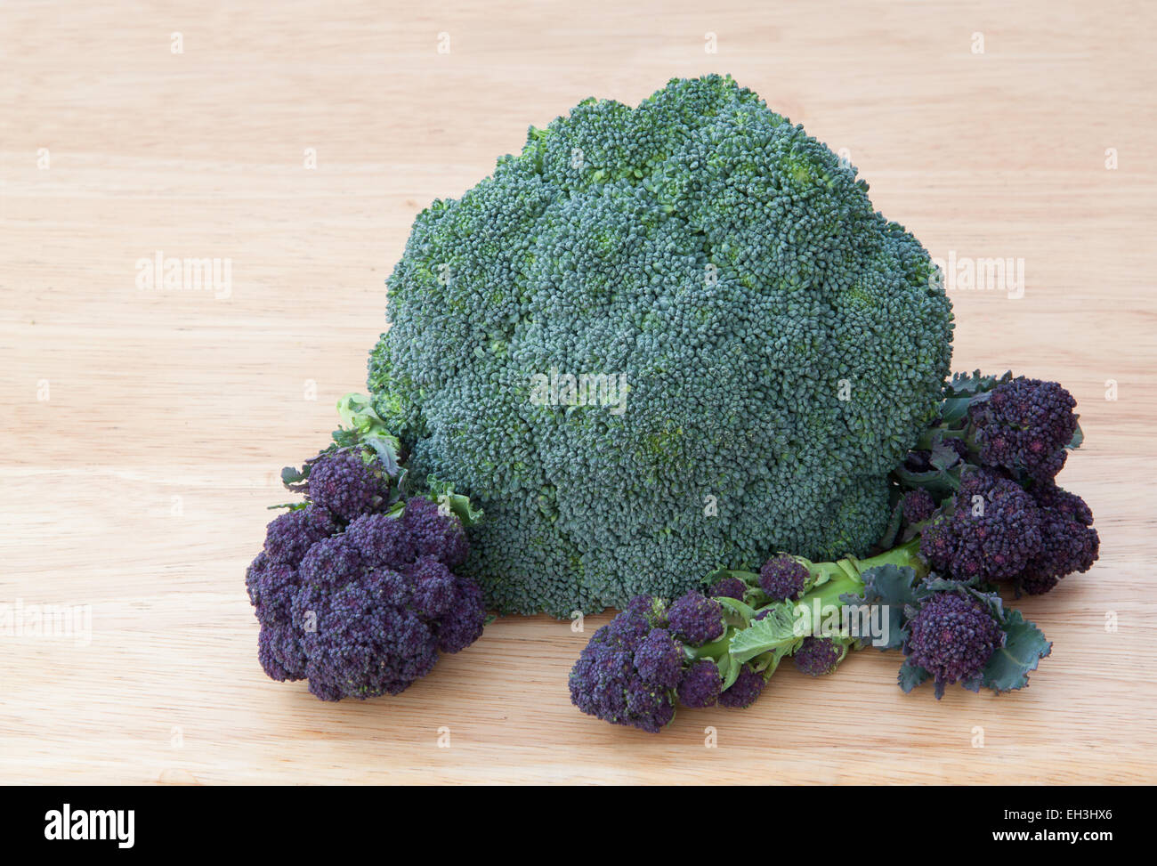 Green and purple sprouting broccoli on a pale wooden board Stock Photo ...