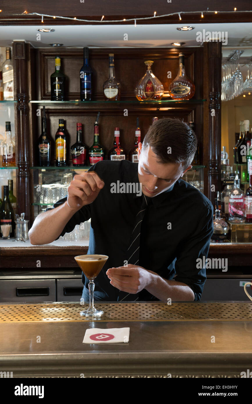 A male barman, bar tender, mixologist makes a fantastic cocktail in a ...