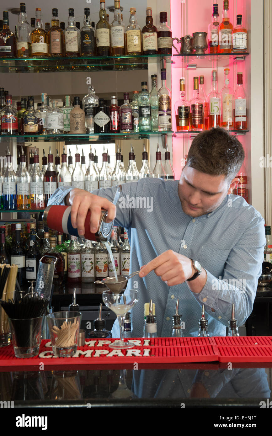A male barman, bar tender, mixologist makes a fantastic cocktail in a ...