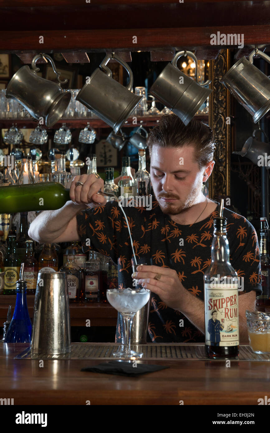 A male barman, bar tender, mixologist makes a fantastic cocktail in a ...