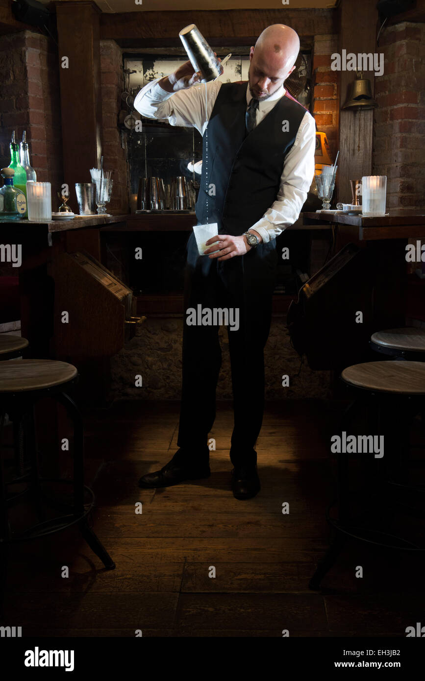 A male barman, bar tender, mixologist makes a fantastic cocktail in a ...