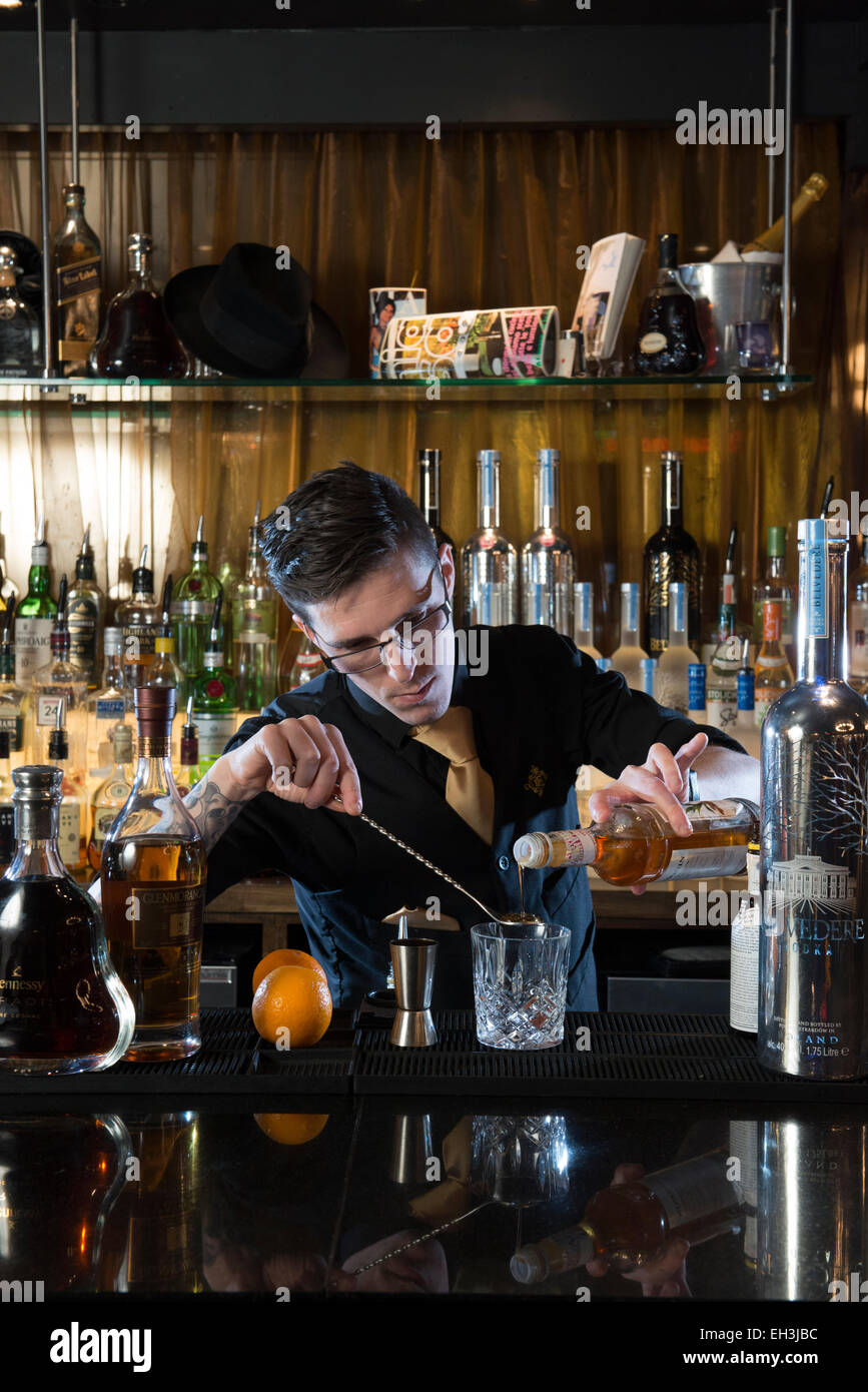 A male barman, bar tender, mixologist makes a fantastic cocktail in a ...