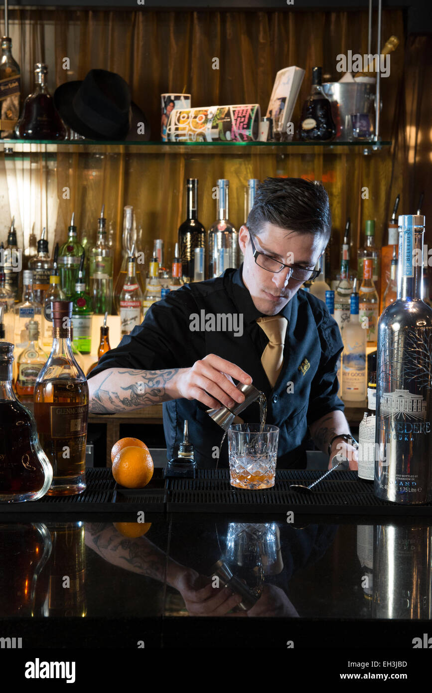 A male barman, bar tender, mixologist makes a fantastic cocktail in a ...
