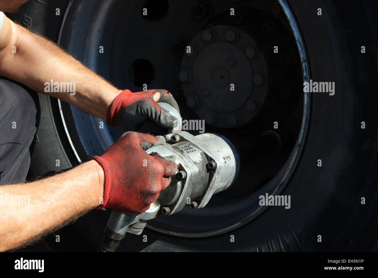 Male mechanic fixing car wheel in workshop Stock Photo - Alamy