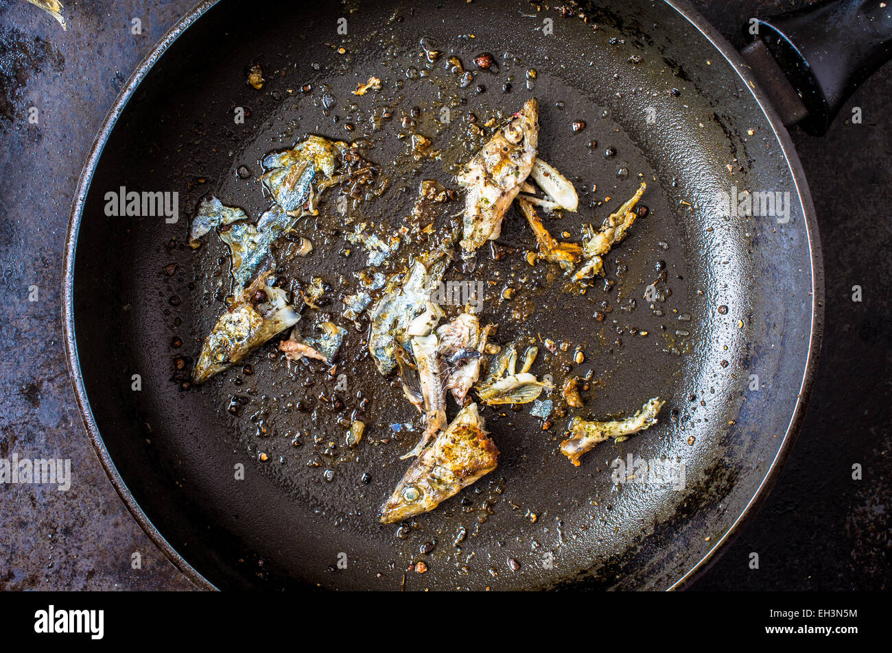 Frying pan with the leftovers of a fried fish Stock Photo - Alamy