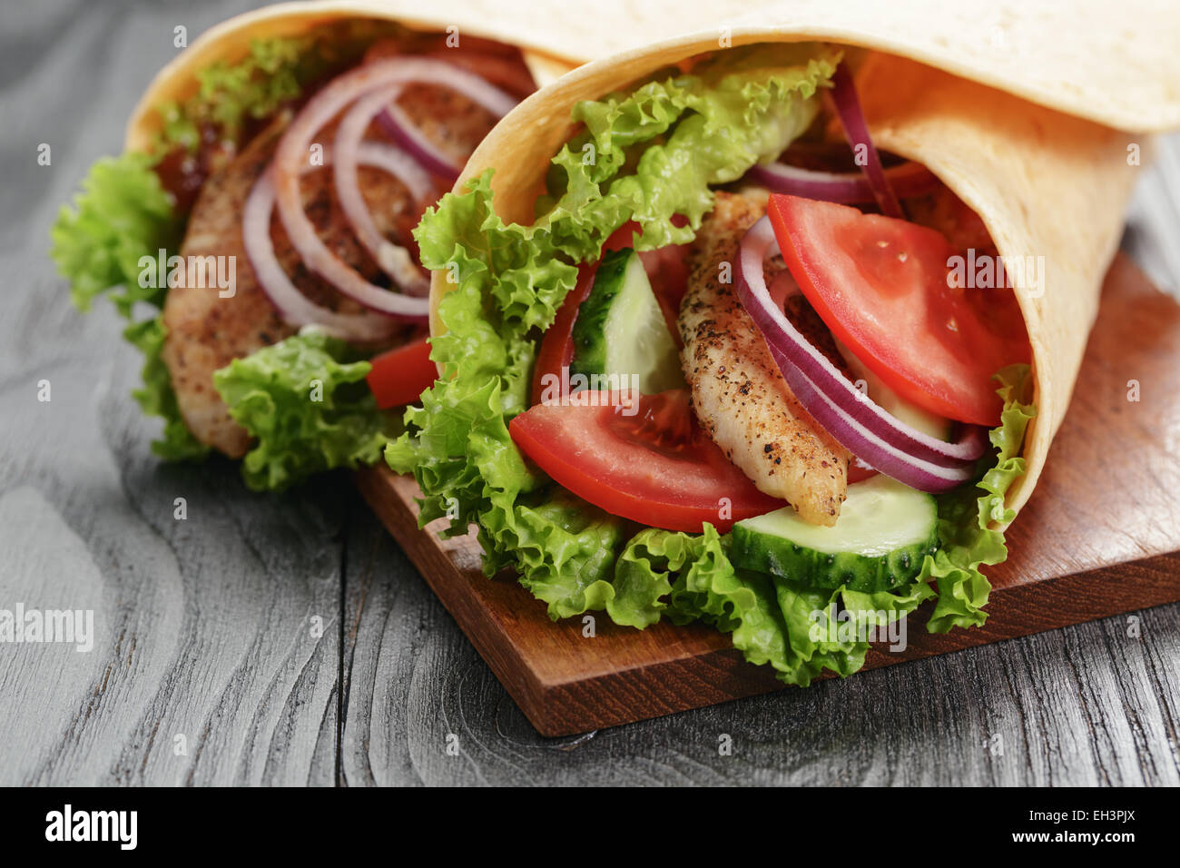 pair of fresh juicy tortilla wraps with chicken and vegetables, on ...