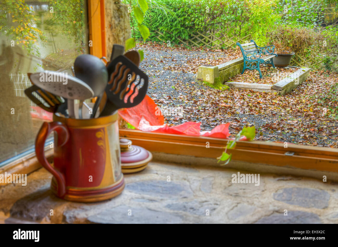 Bench in the garden seen through old kitchen window with foliage red ...