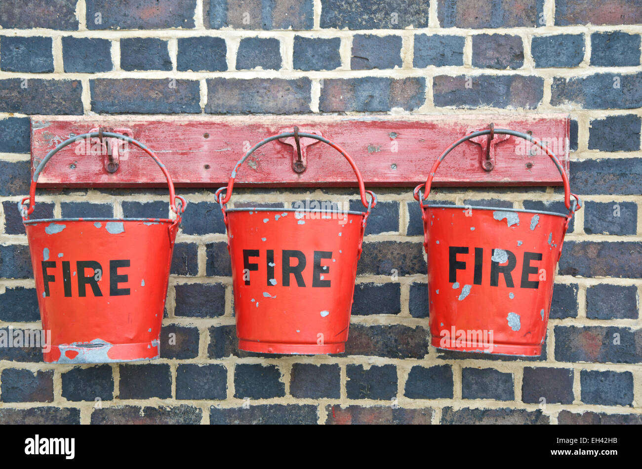 Three red fire buckets hanging against a brick wall Stock Photo - Alamy