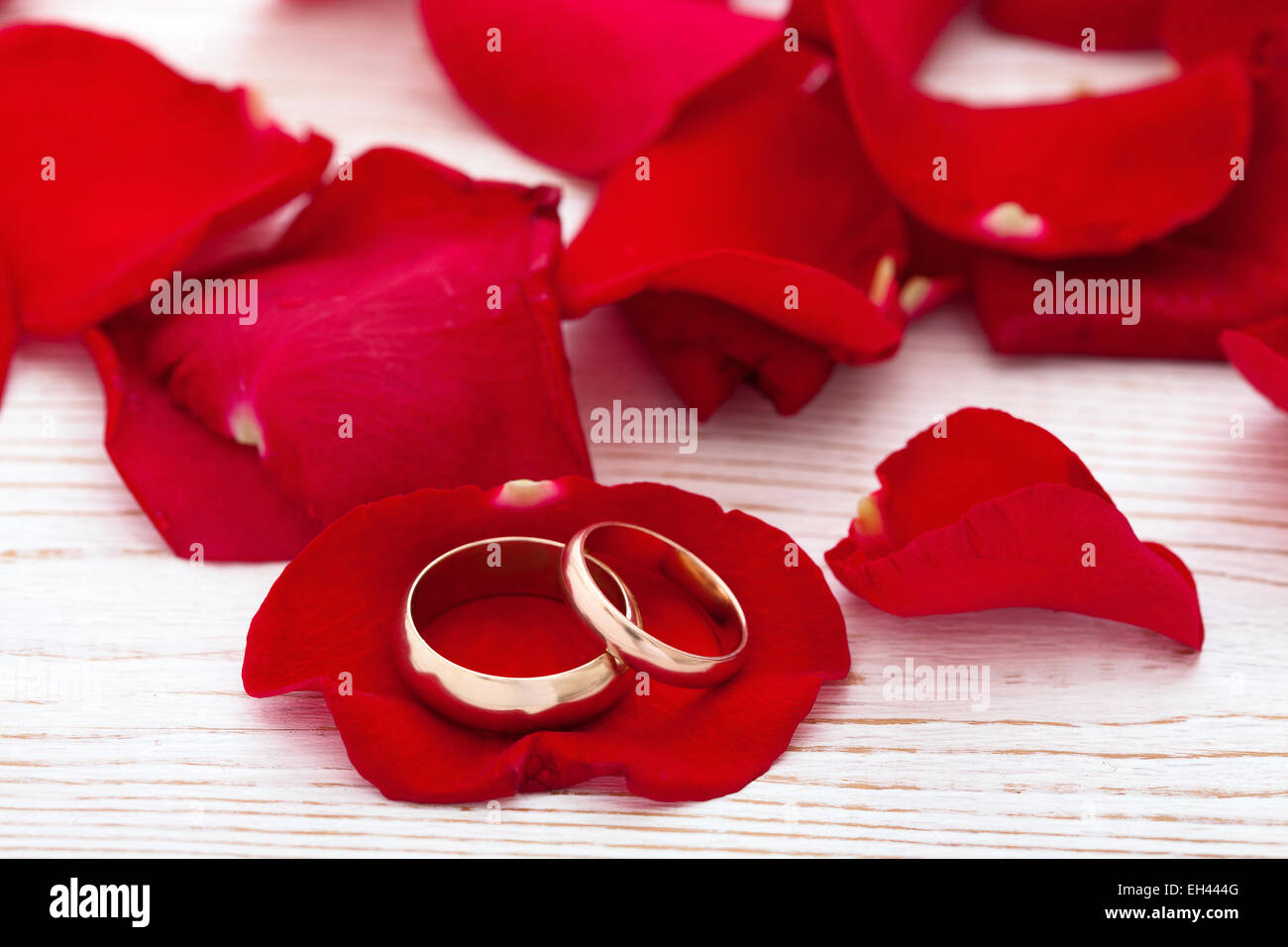 Wedding rings and wedding bouquet of red roses petals Stock Photo - Alamy