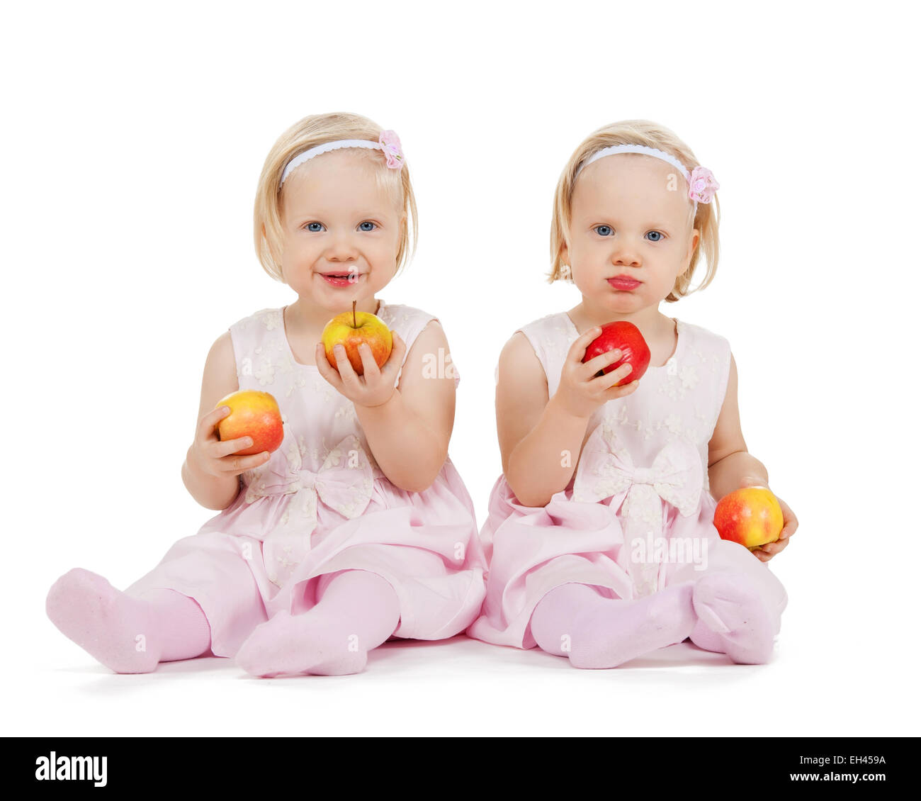 two identical twin girls playing with apples Stock Photo - Alamy