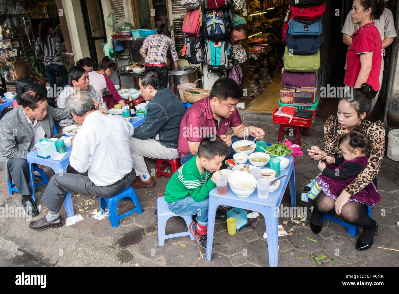 Sitting on plastic stools for a street food meal on the scooter filled ...