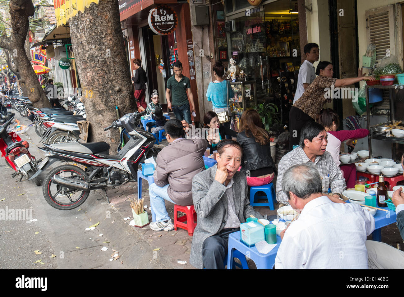 Sitting on plastic stools for a street food meal on the scooter filled ...