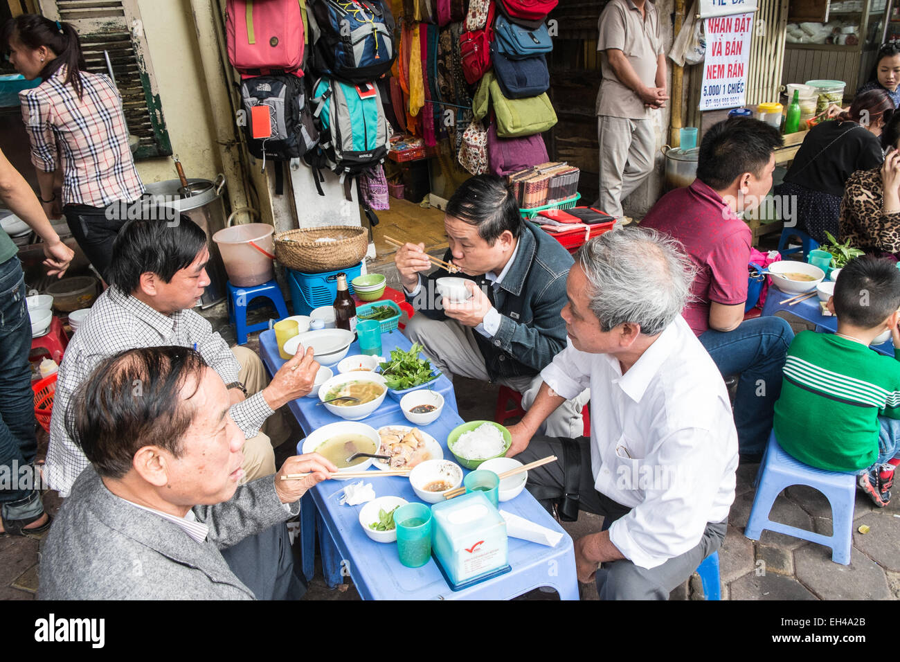 Sitting on plastic stools for a street food meal on the scooter filled ...