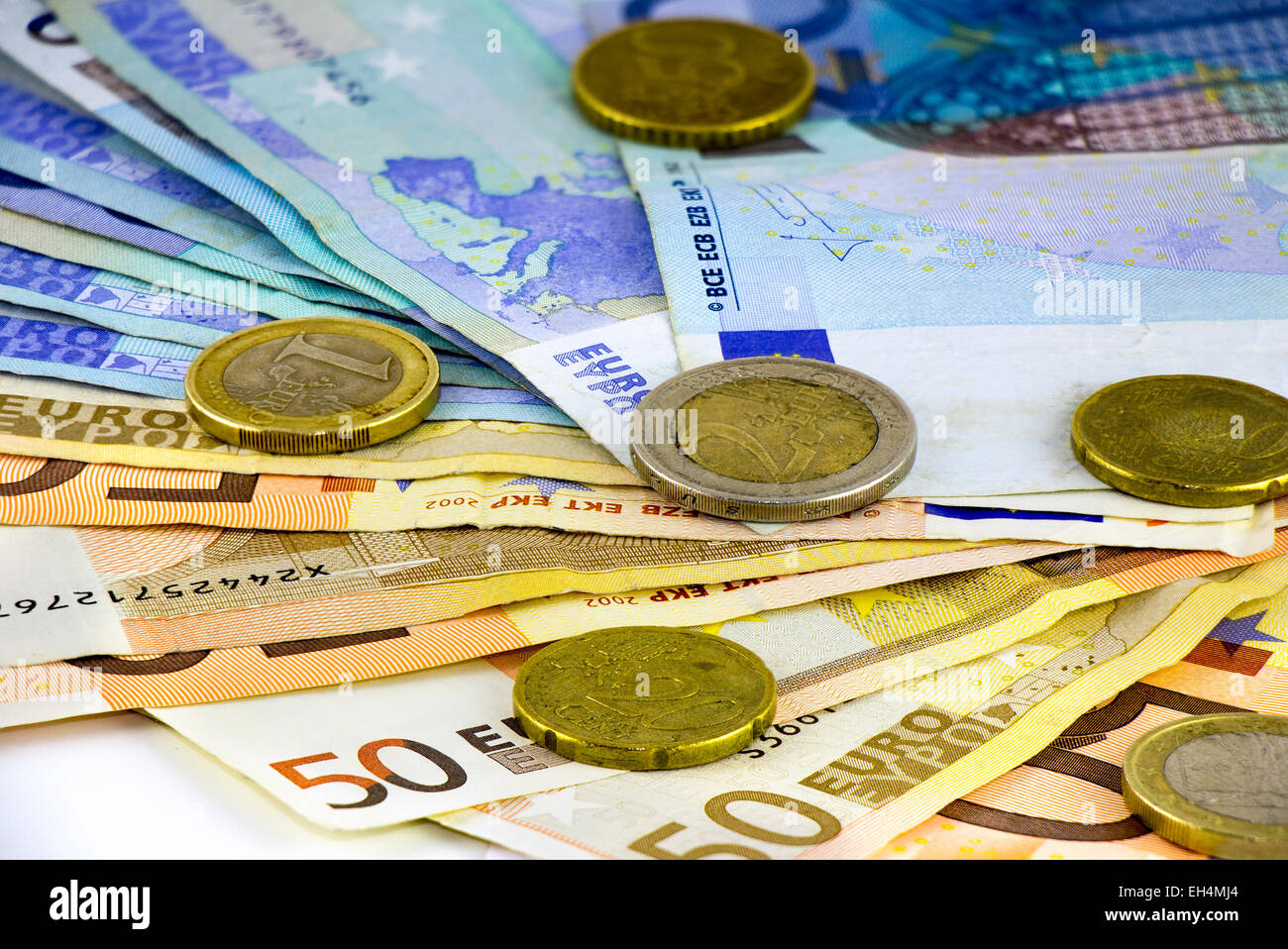 A bundle of Euro banknotes and coins isolated on a white background ...