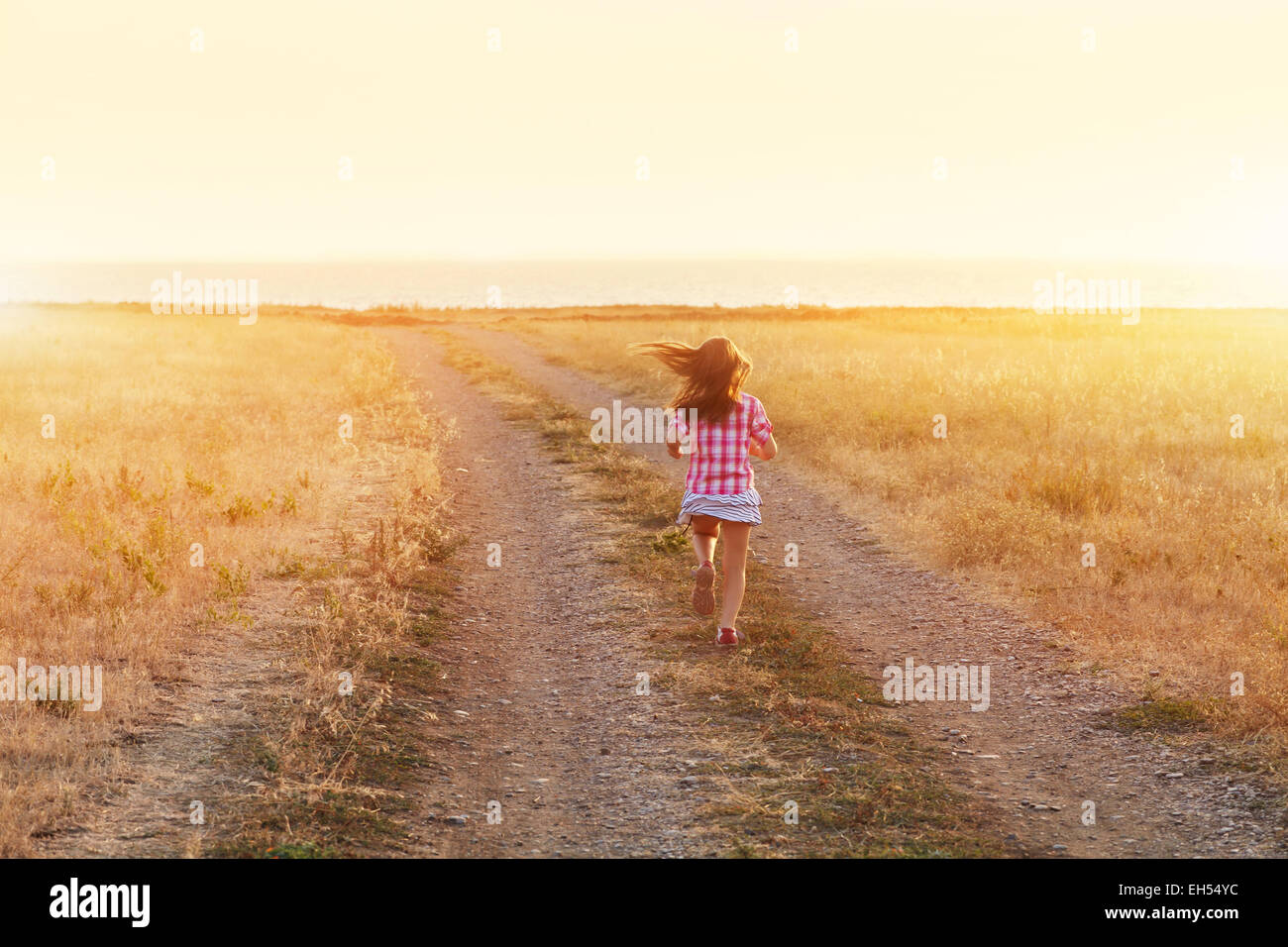 Little girl running down the road at sunset. carefree. inspiration ...