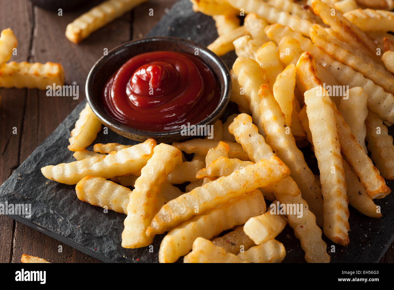 Unhealthy Baked Crinkle French Fries with Ketchup Stock Photo - Alamy