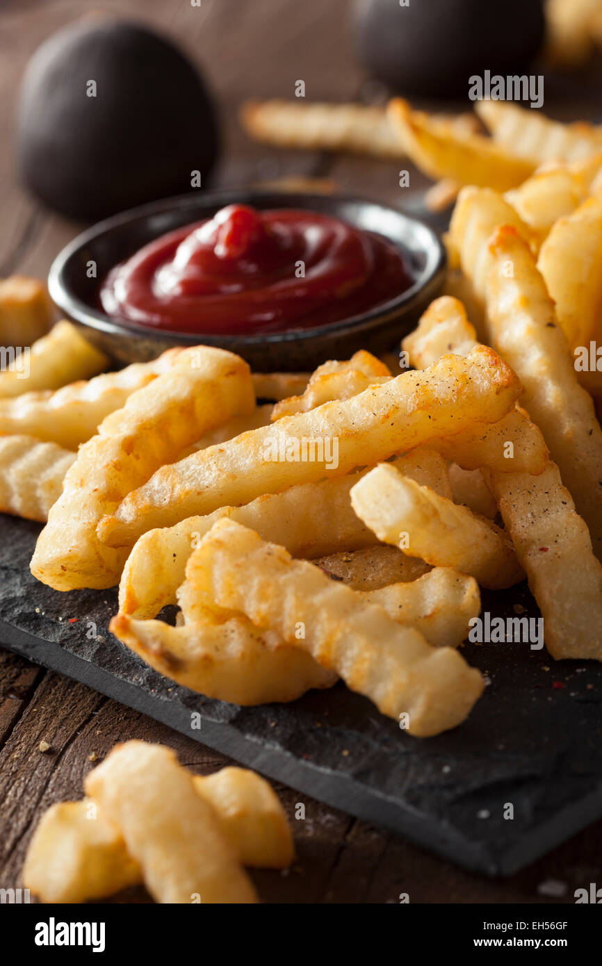 Unhealthy Baked Crinkle French Fries with Ketchup Stock Photo - Alamy