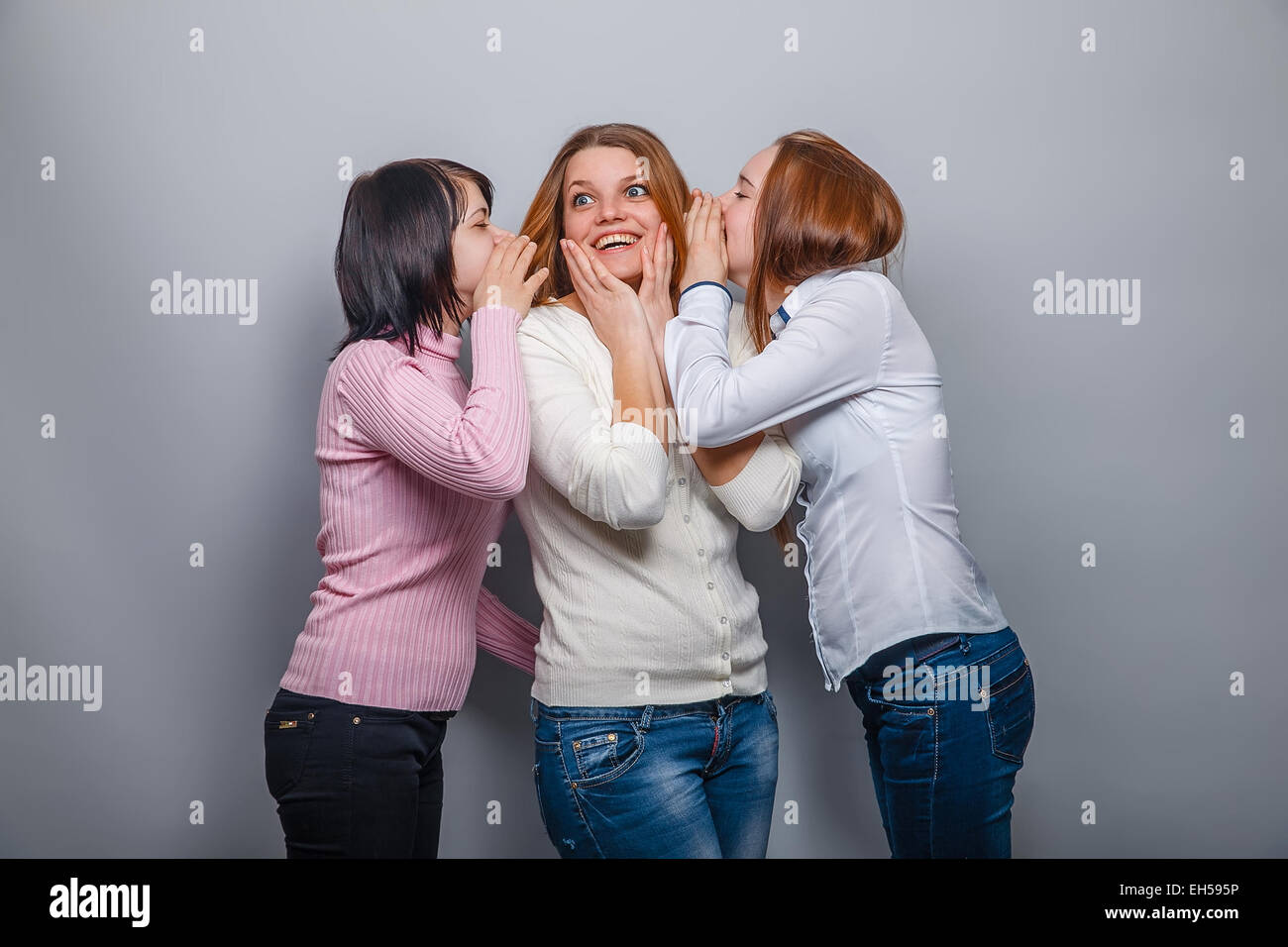 two girls European appearance whisper in the ear of the third the ...