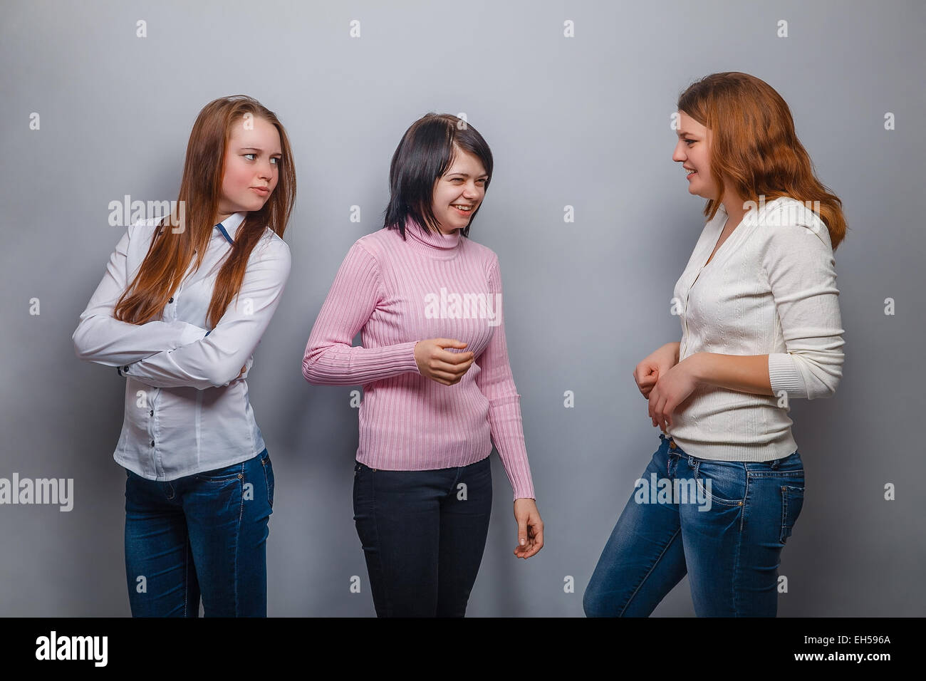 Three girls girlfriends talking two, one was offended on a gray ...