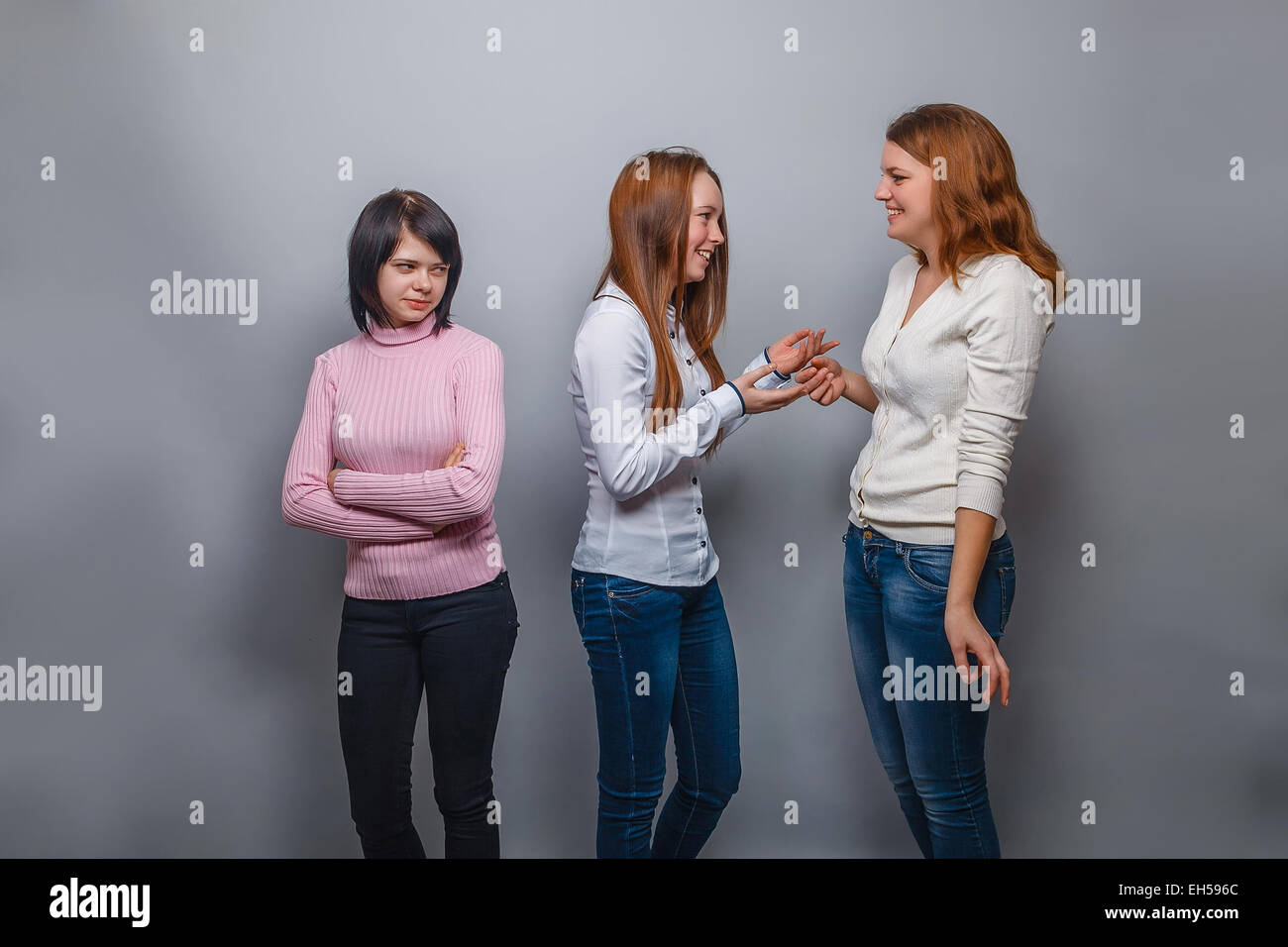 Three girls girlfriends talking two, one was offended on a gray ...