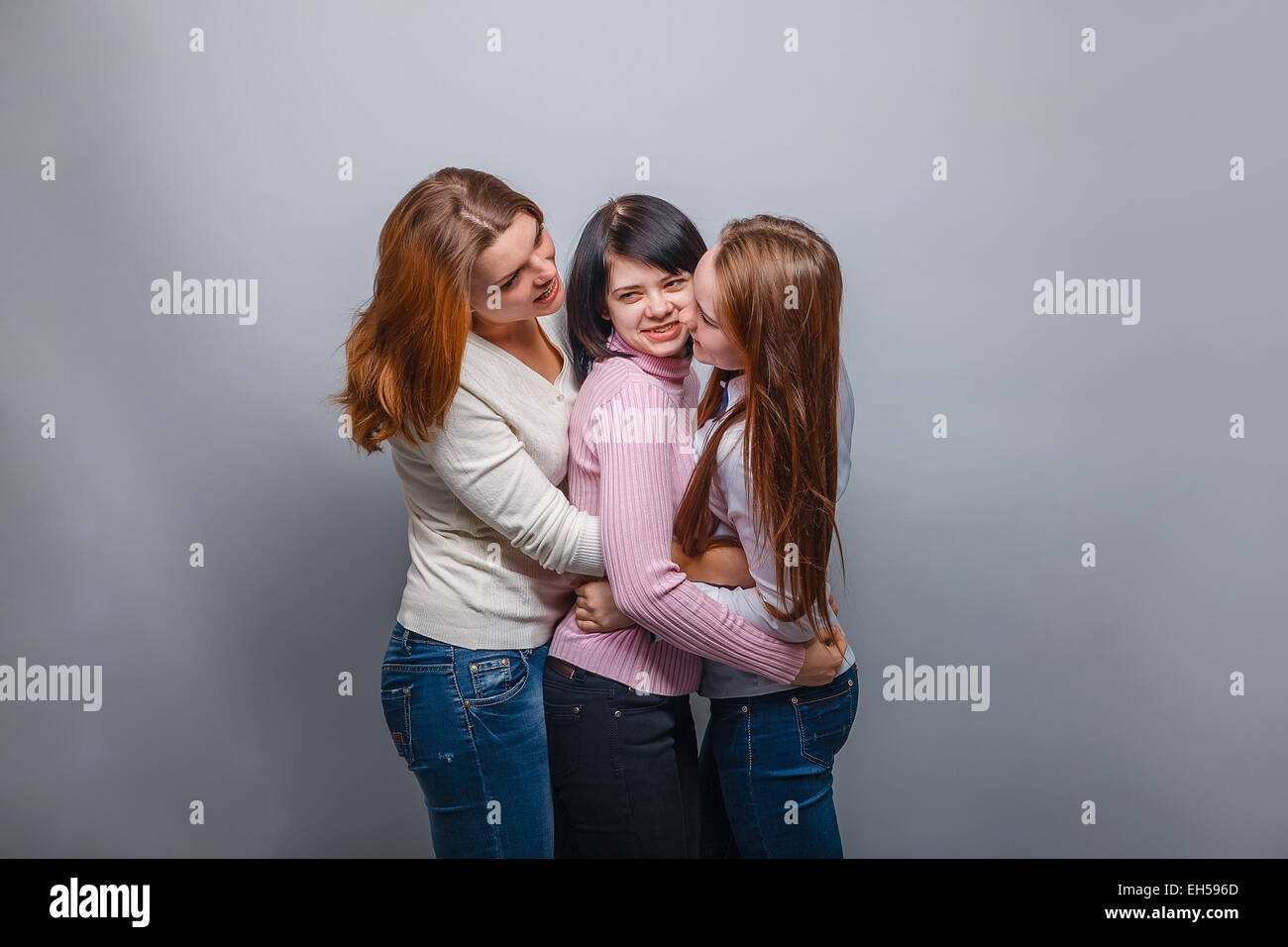 Three girls girlfriends, cuddling on a gray background Stock Photo - Alamy