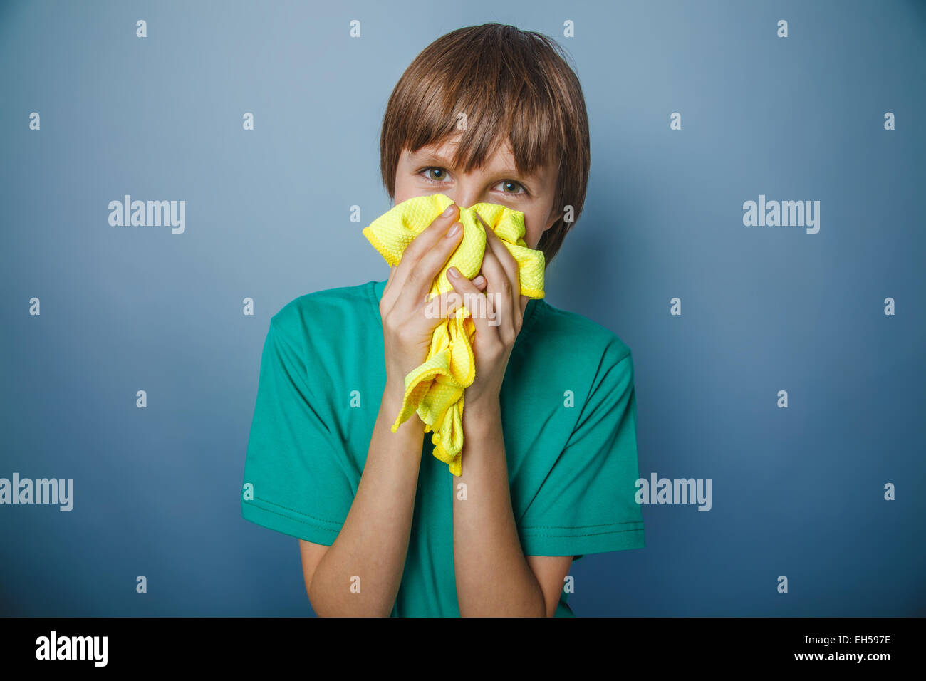 boy teenager European appearance in a green T-shirt blows his nose in a ...