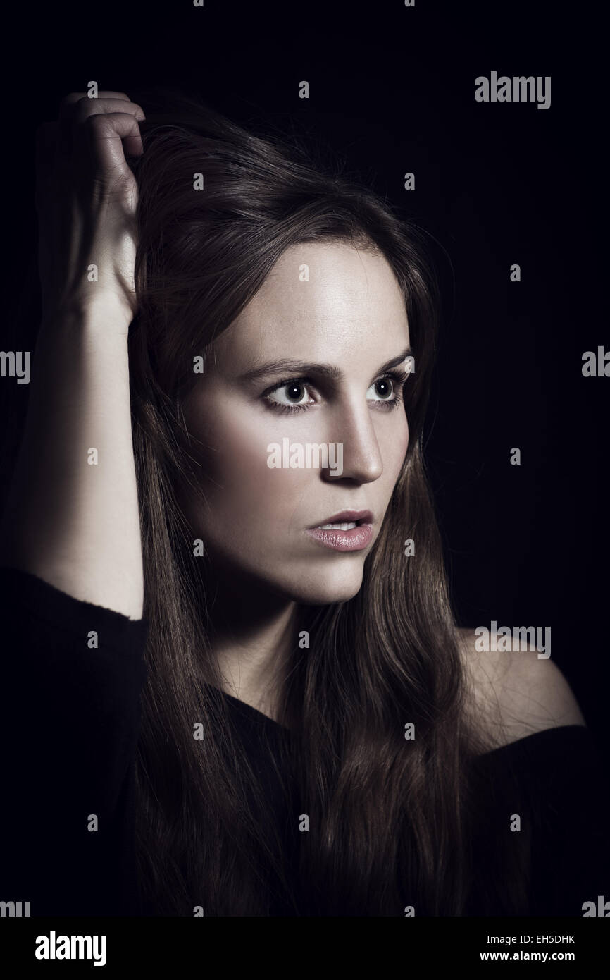 Studio shot of a young natural woman / girl with lowkey lighting. Black ...