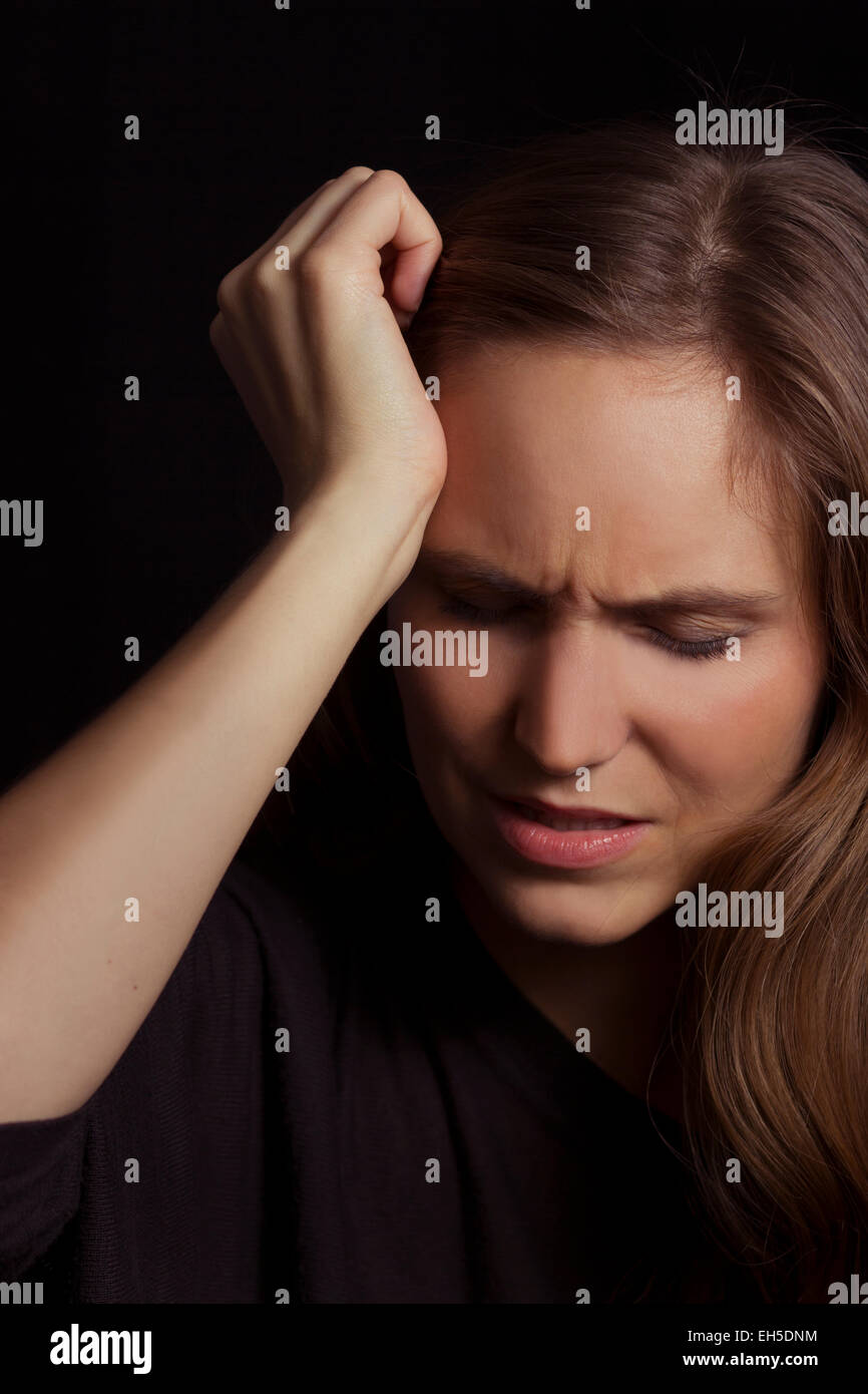 Studio shot of a young woman / girl with migraine / headache / anger ...