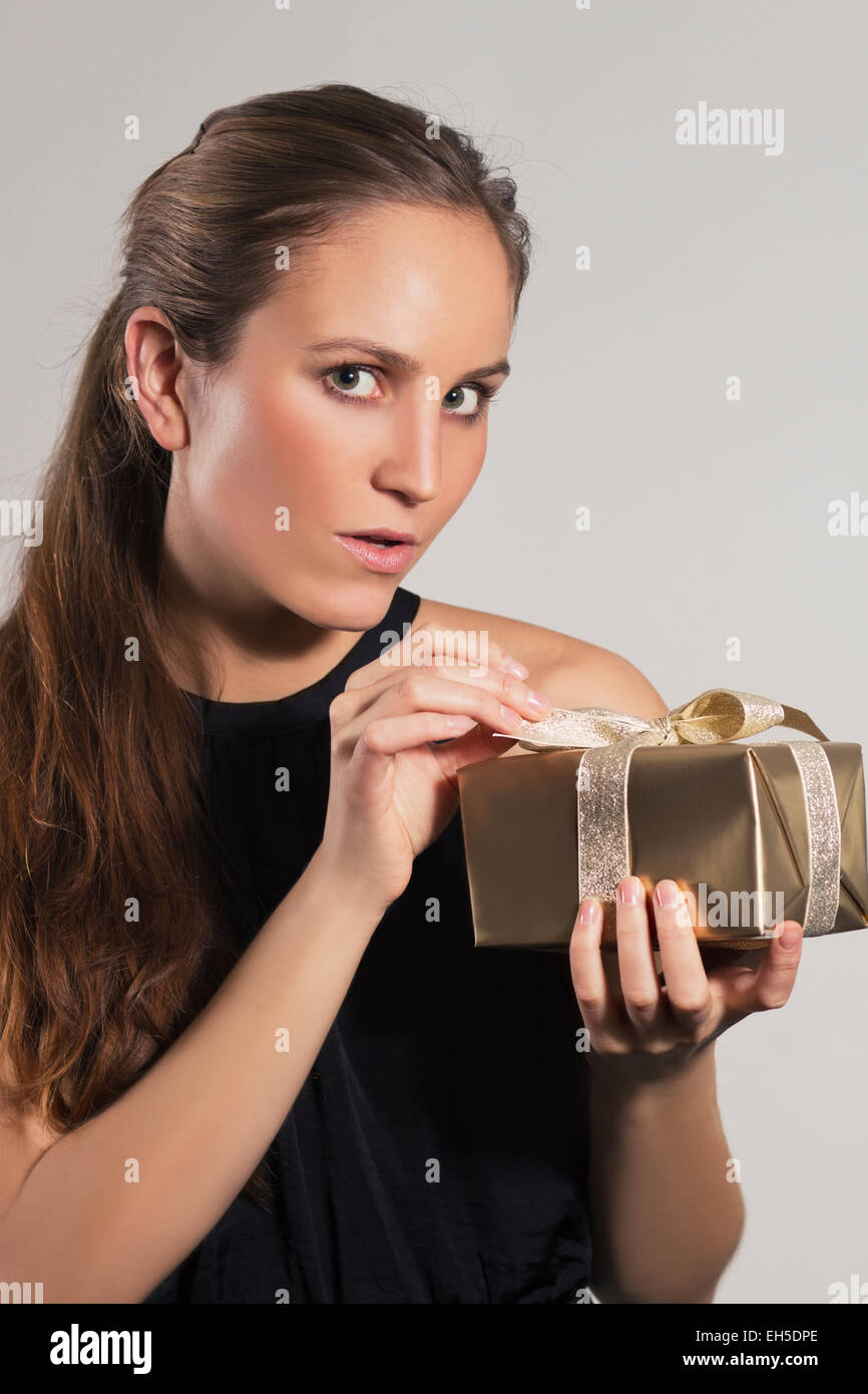 Excited young attractive woman open christmas gift or birthday present ...