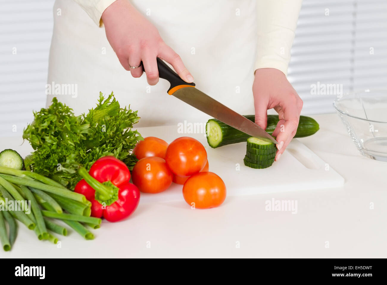 Woman in a white kitchen making salad with vegetables Stock Photo - Alamy