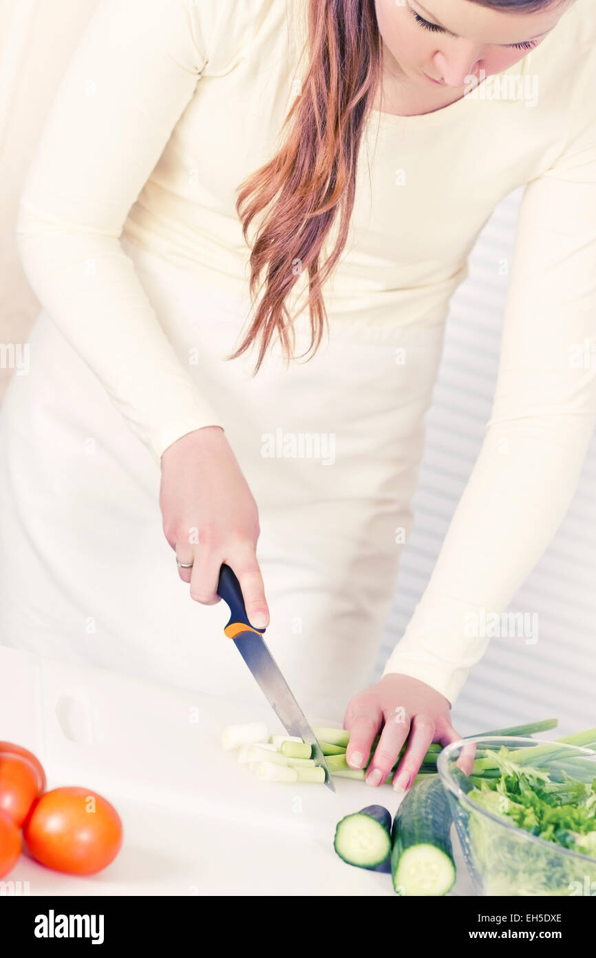 Woman in a white kitchen making salad with vegetables Stock Photo - Alamy
