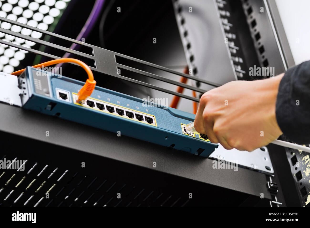 IT consultant inserting / connecting a network cable into a switch ...