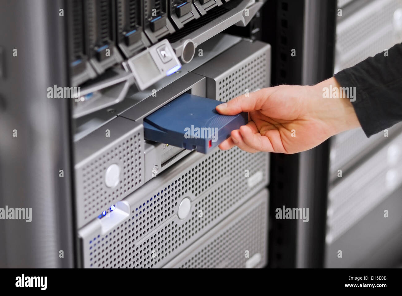 A close-up of a IT engineer / technician insert a backup tape in a ...