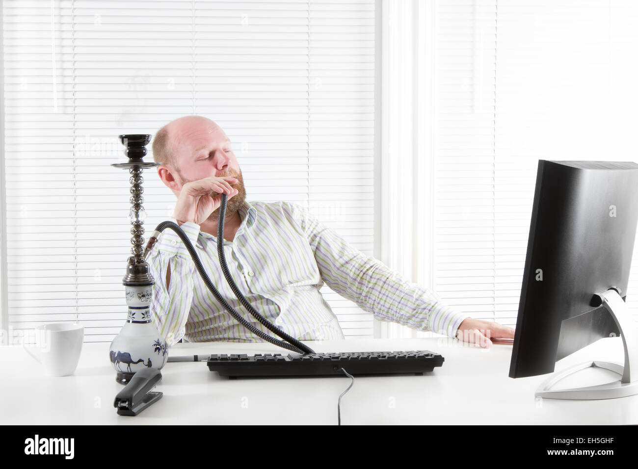 Office worker smoking water pipe in his office Stock Photo - Alamy