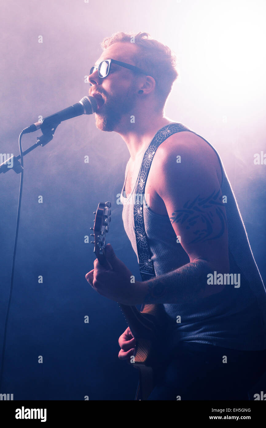 Young man playing rock concert. Sings and play guitar Stock Photo - Alamy