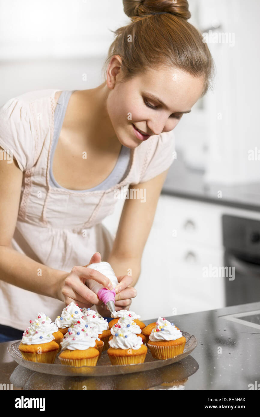 A woman baking muffins or cupcakes in white kitchen Stock Photo - Alamy
