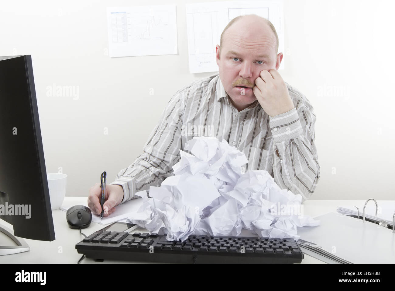 Busy and overworked office worker with a heap of paper at the office ...