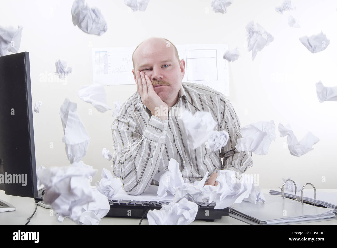 Busy and overworked office worker with flying paper around in the ...