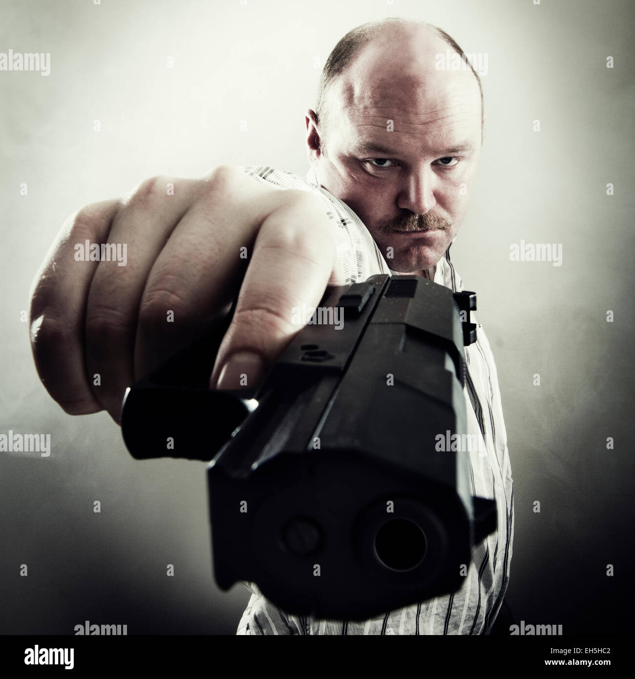 A man with a mustache points gun at camera. Smoke in the background ...