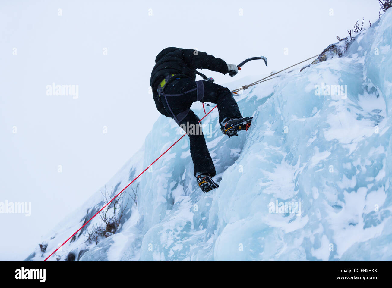 Ice climber scaling ice cliff Stock Photo - Alamy