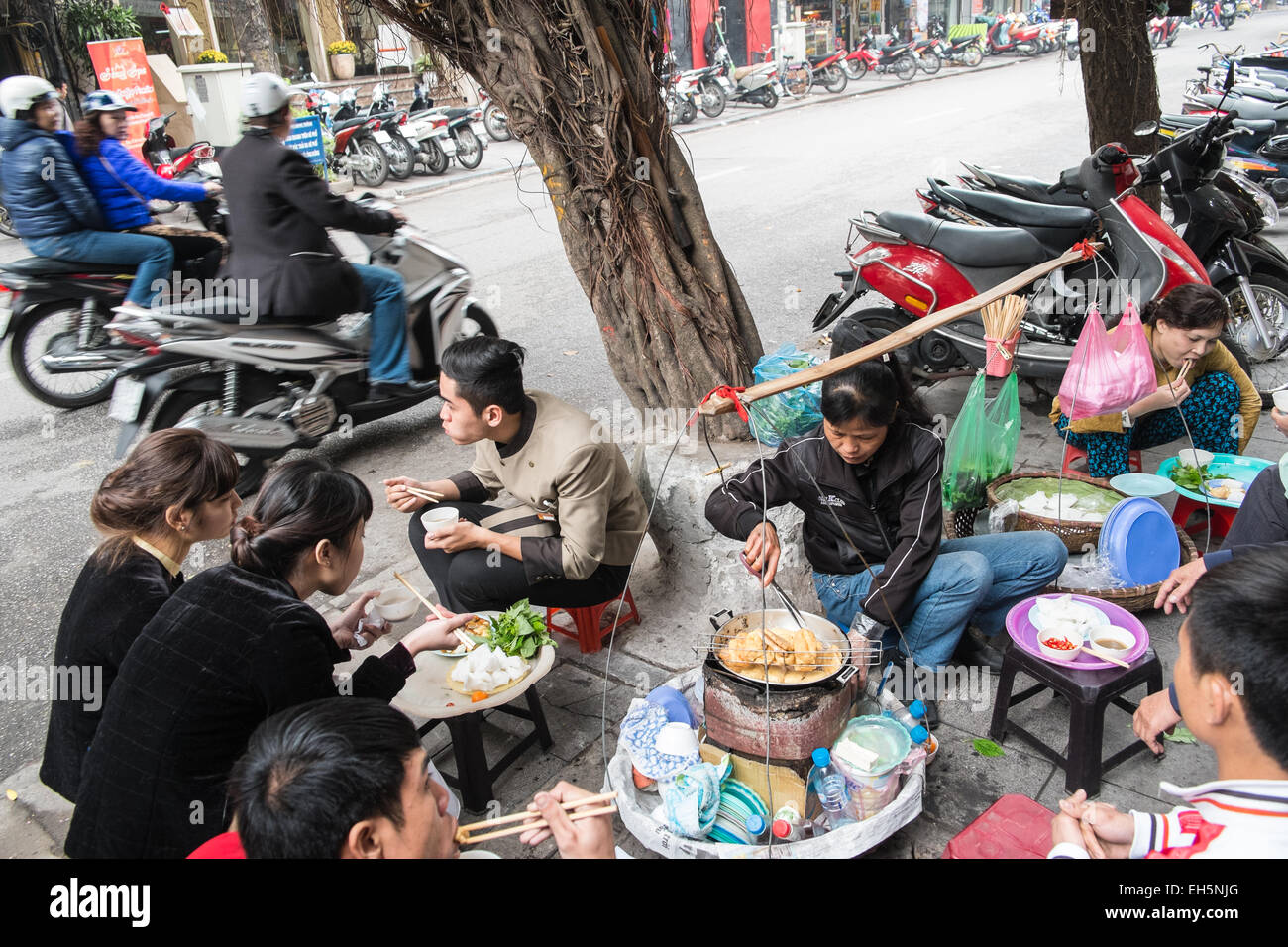 Sitting on plastic stools for a street food meal on the scooter filled ...